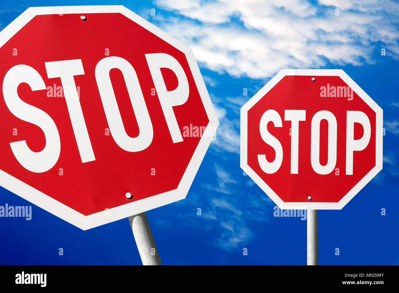 Two Stop signs against blue sky with clouds Stock Photo - Alamy