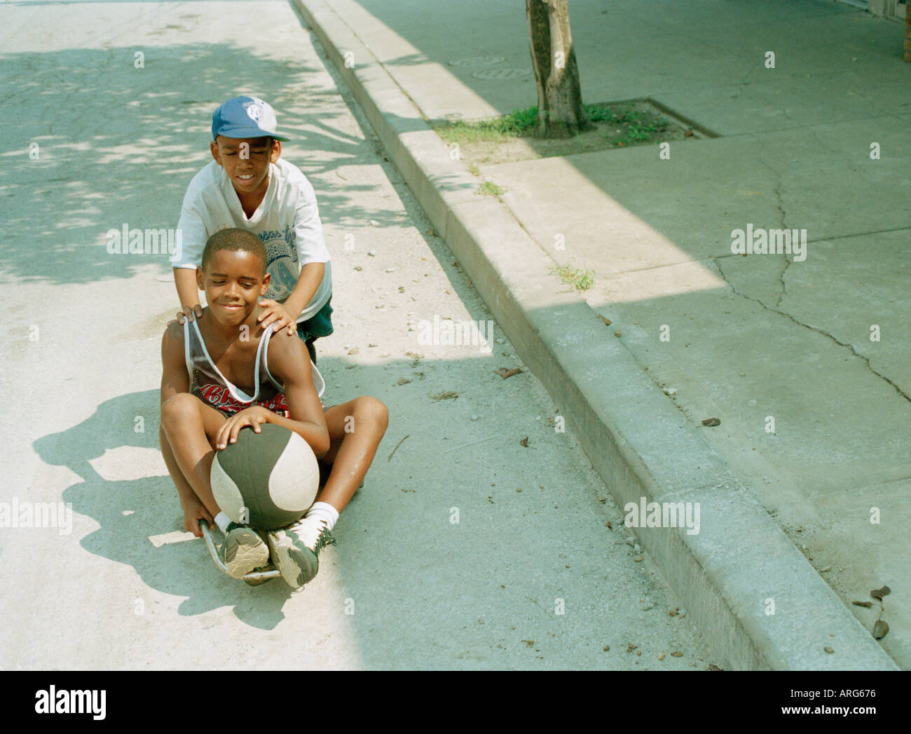 boy pushing friend on skateboard Stock Photo - Alamy