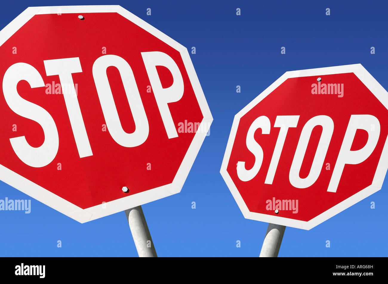 Two Stop signs and blue sky background Stock Photo - Alamy