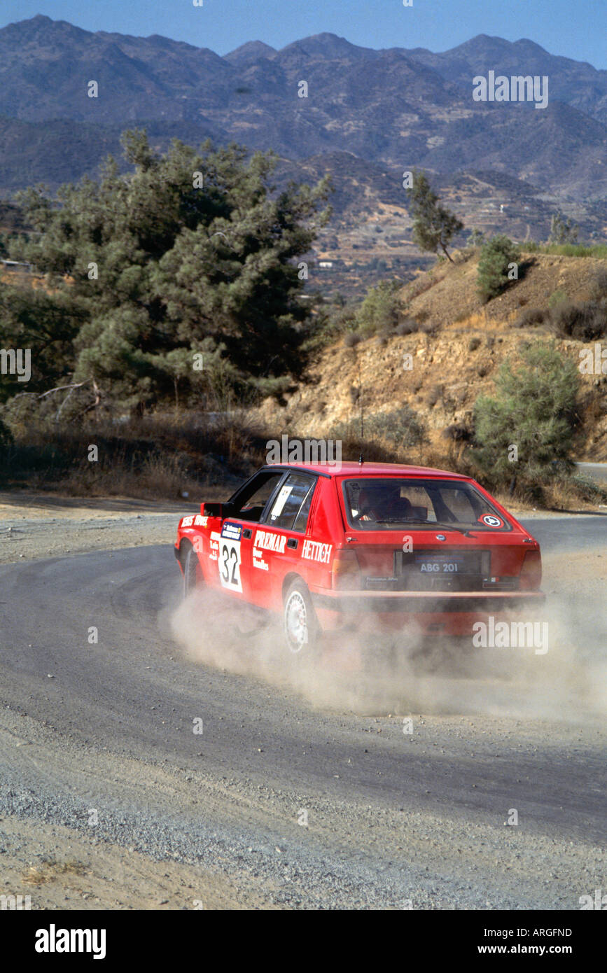 A brightly coloured rally car numbered 32 leaves a cloud of dust as it ...