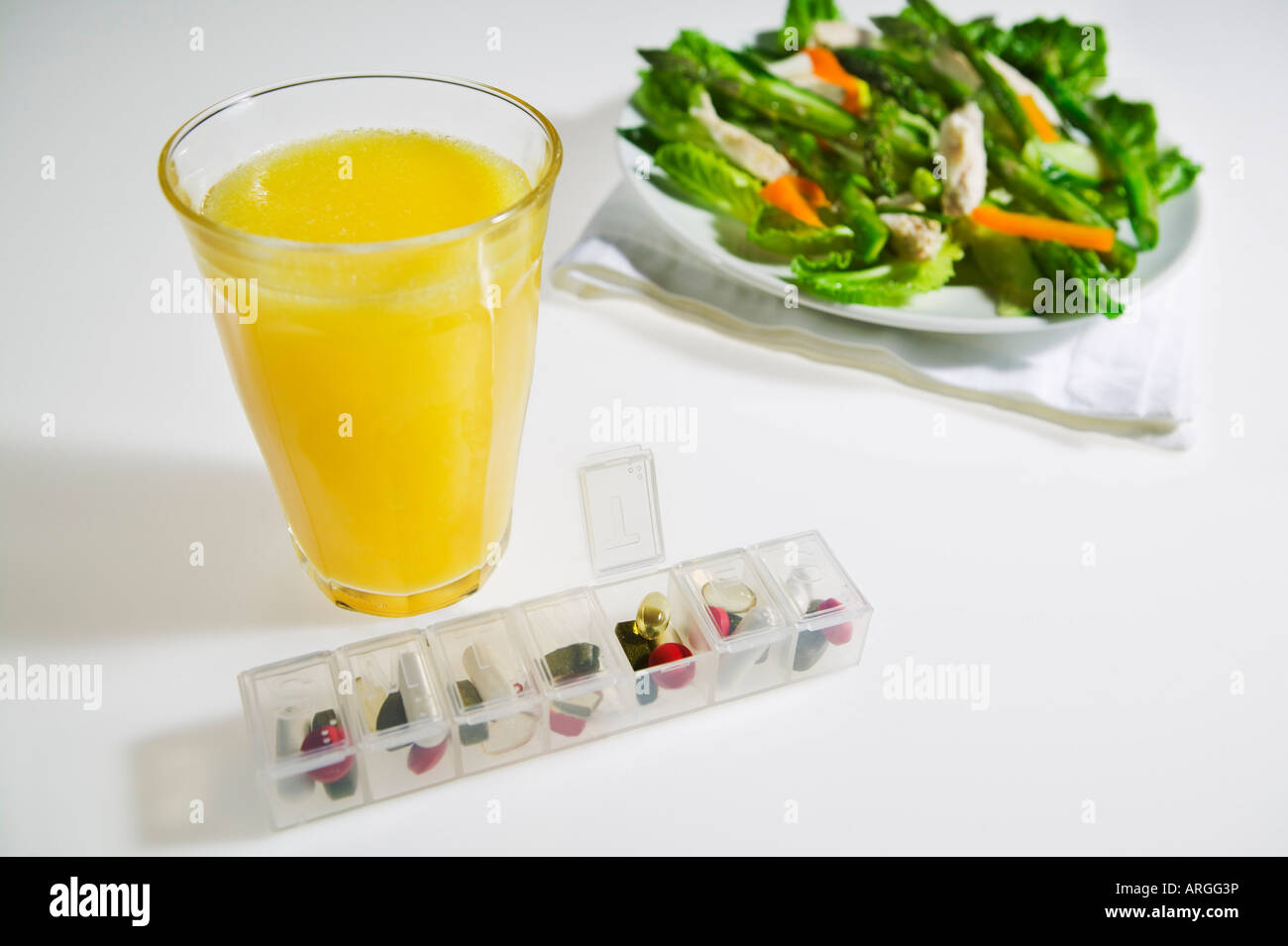 Chicken Salad, Orange Juice and Pill Dispenser Stock Photo - Alamy
