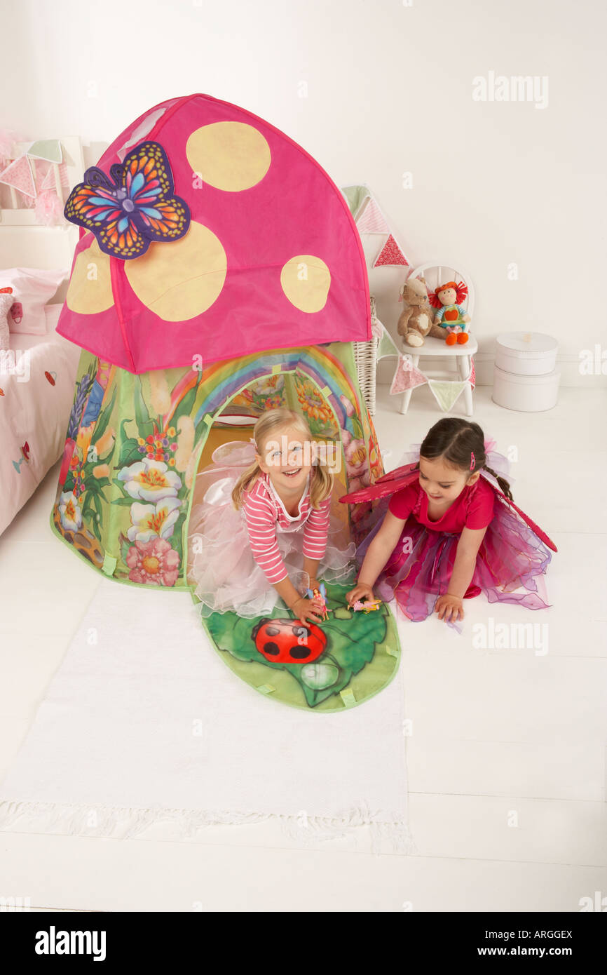 Two girls play dress up in fairy costumes and play with toy fairies ...