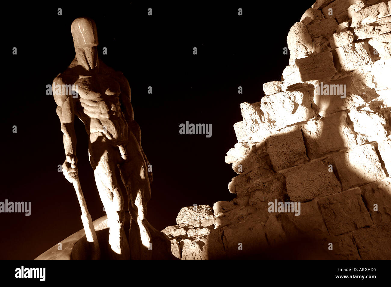 Israeli sculpture of powerful alien- like being on a rock face in small ...