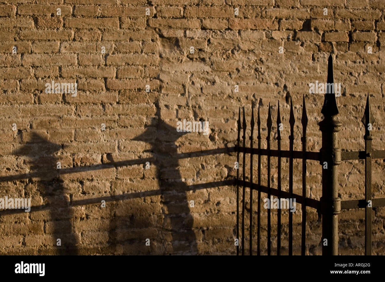 Dark iron gate with its shadow on the wall Stock Photo - Alamy