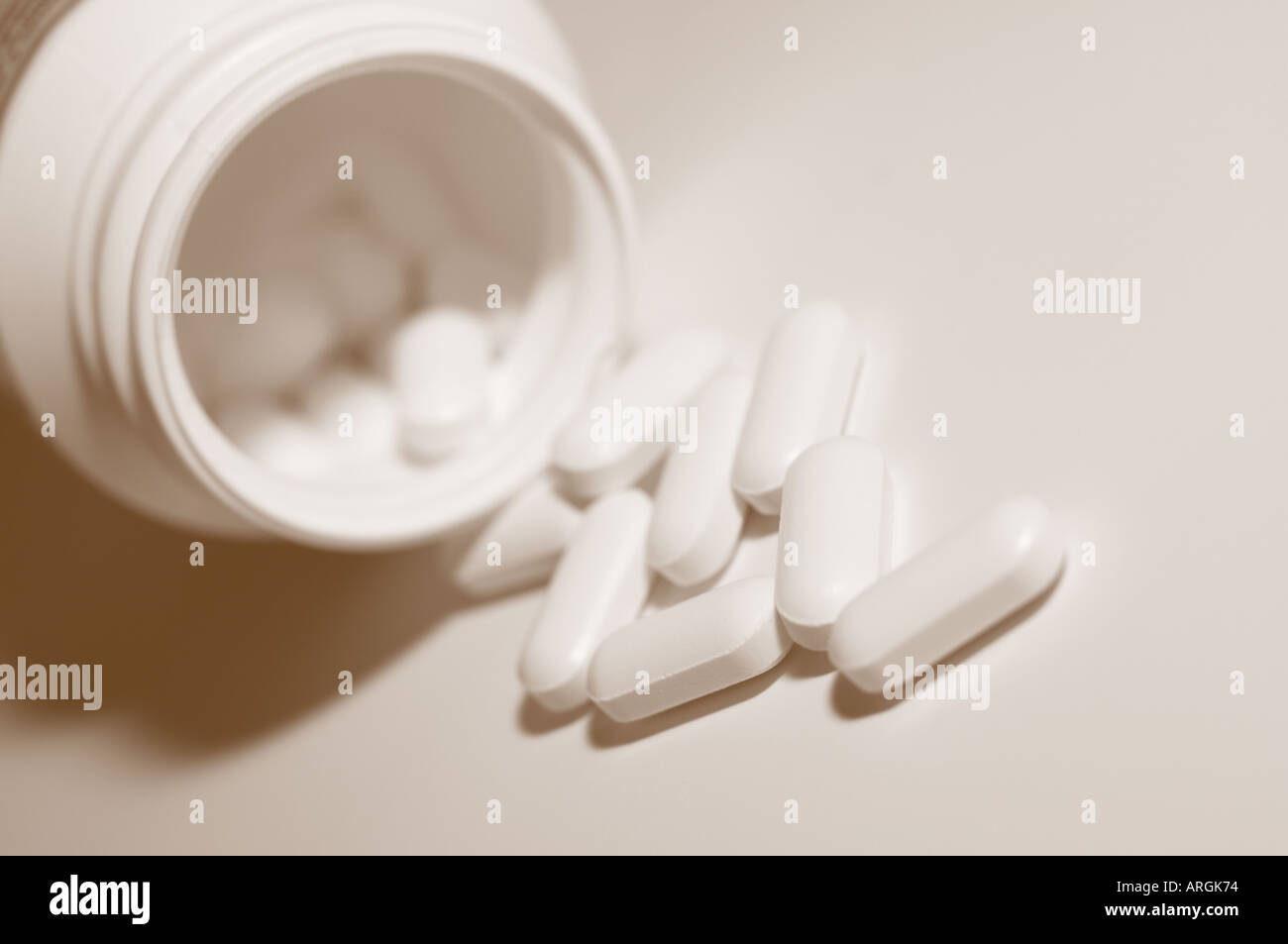 Small white medicinal tablets spilling from a bottle Stock Photo - Alamy