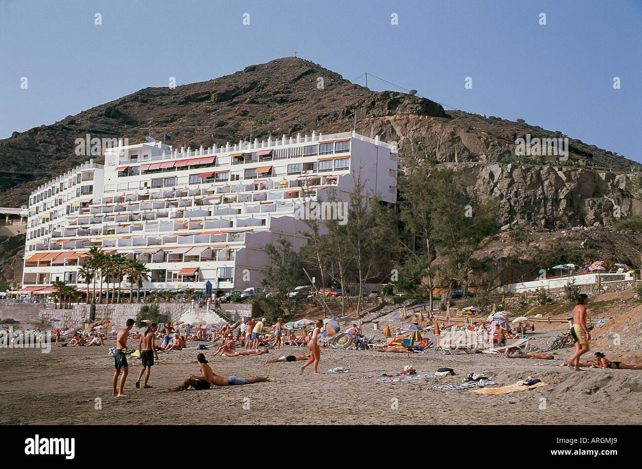 Behind the tourists enjoying the sun sea and sand on the busy beach a ...