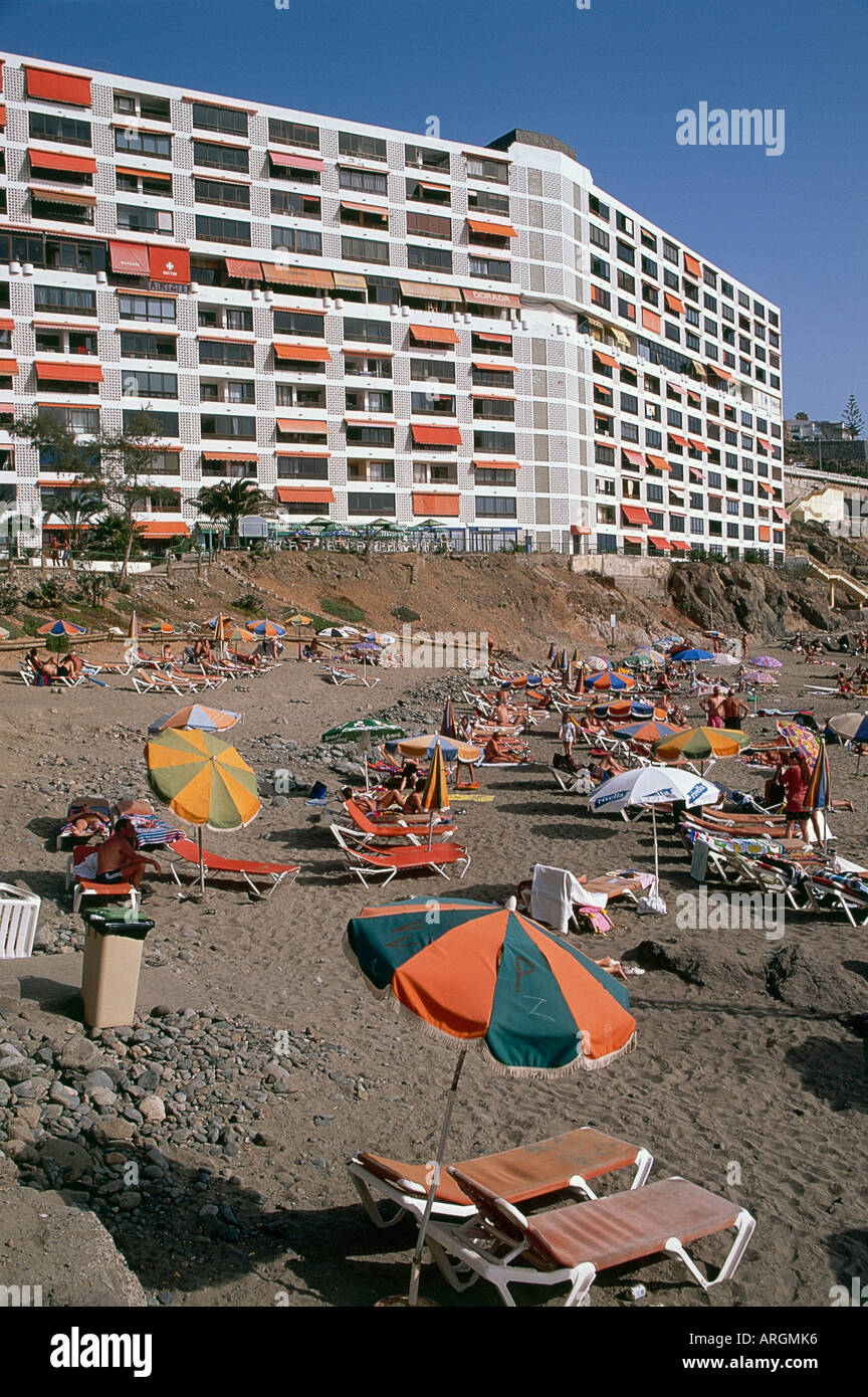 Behind the tourists enjoying the sun sea and sand on the busy beach a ...