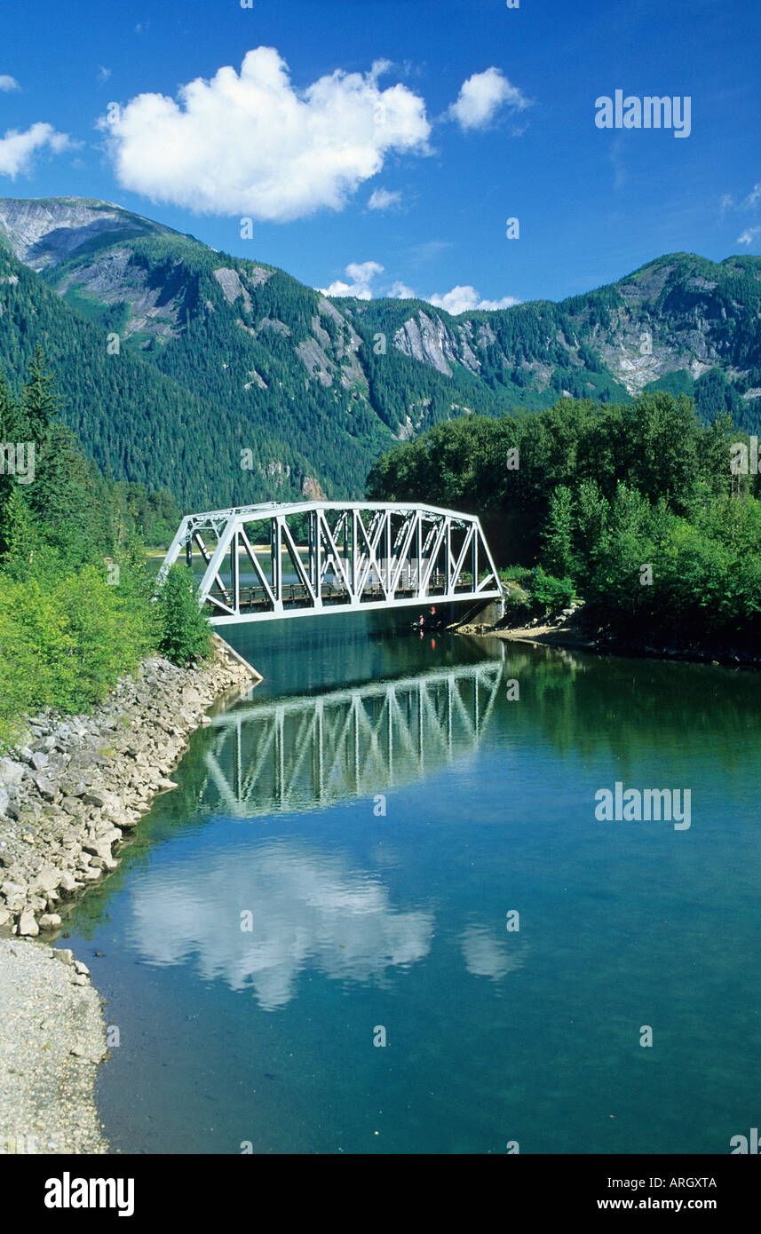 A metal framed bridge spanning the tree lined Skeena River with the ...