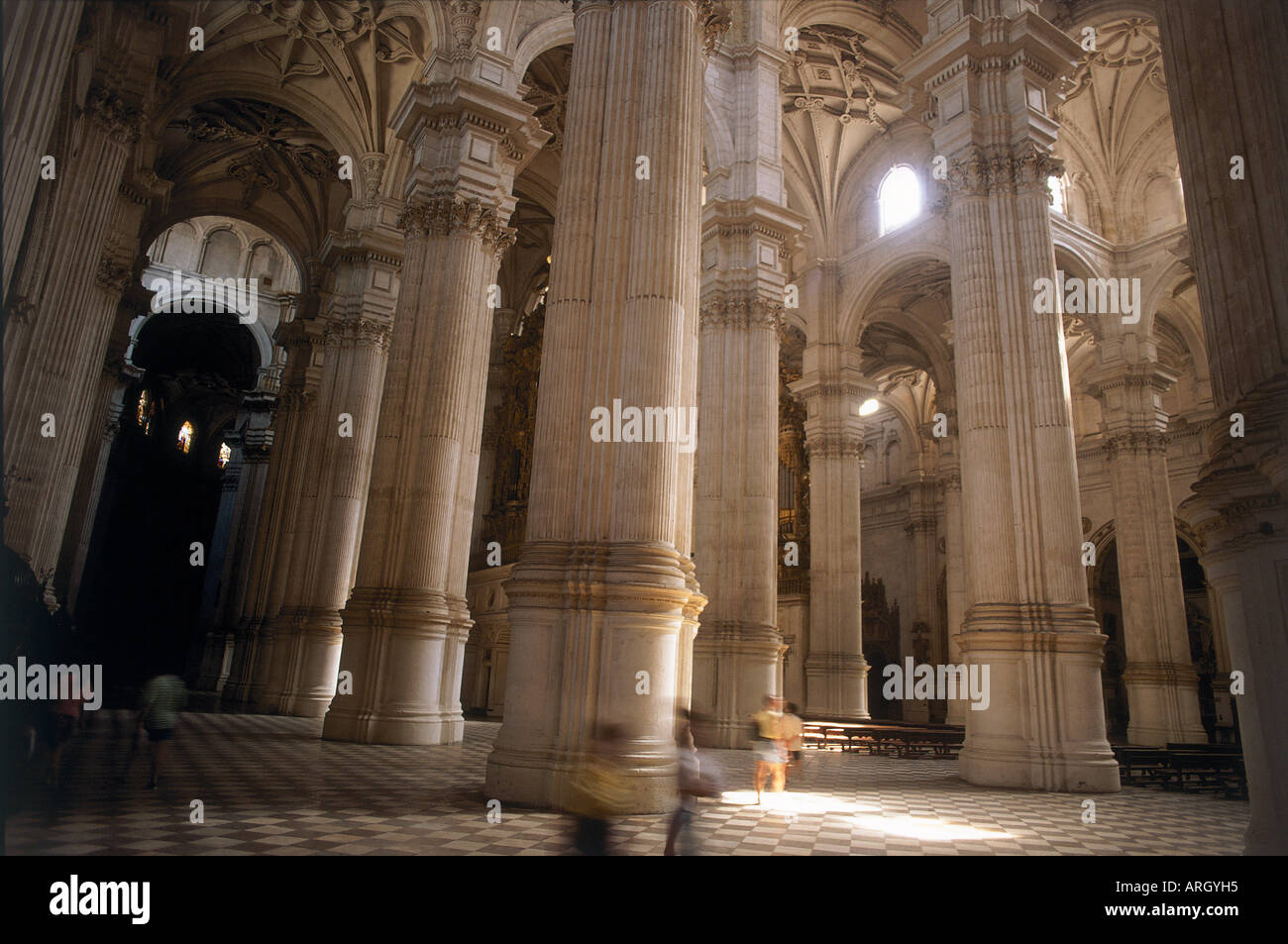 A lone figure stands dwarfed by the massive columns and ornate archways ...