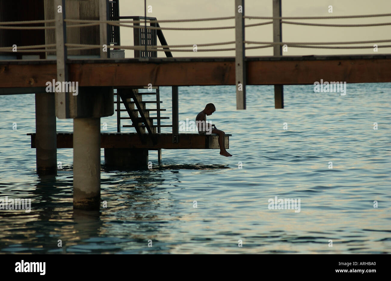 A man sitting on steps of a pier Moorea Tahiti French Polynesia South ...