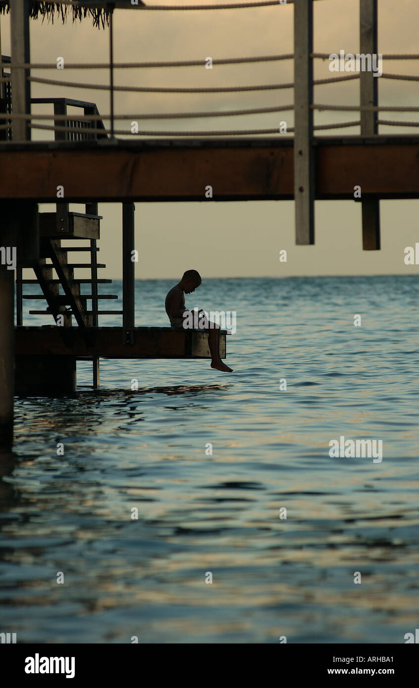 A man sitting on steps of a pier Moorea Tahiti French Polynesia South ...