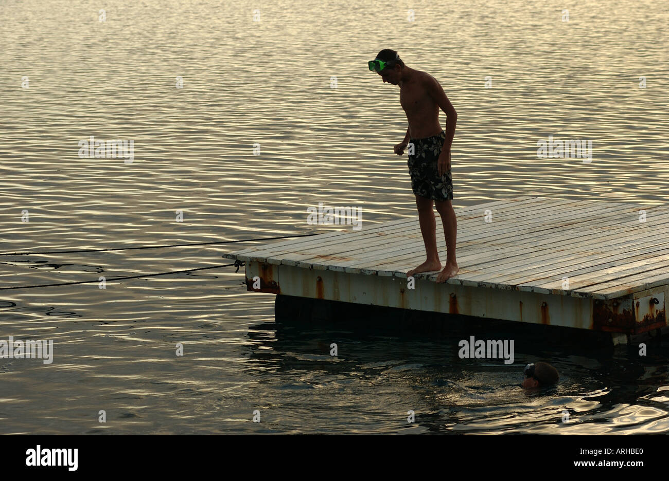 A young man looking into the water standing on a raft Moorea Tahiti ...