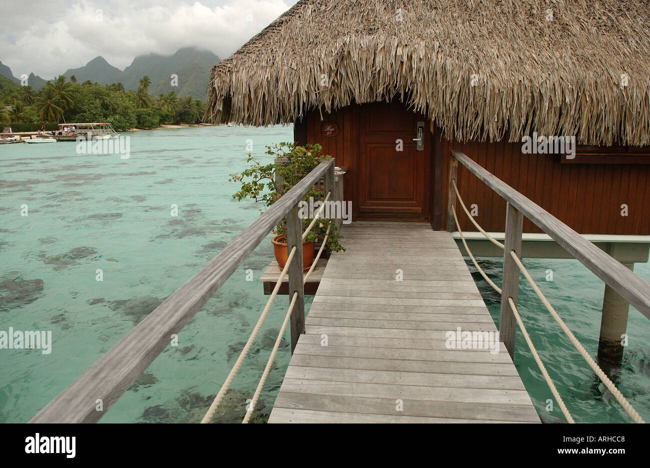 A pier with a thatched roof structure supported by stilts Moorea Tahiti ...