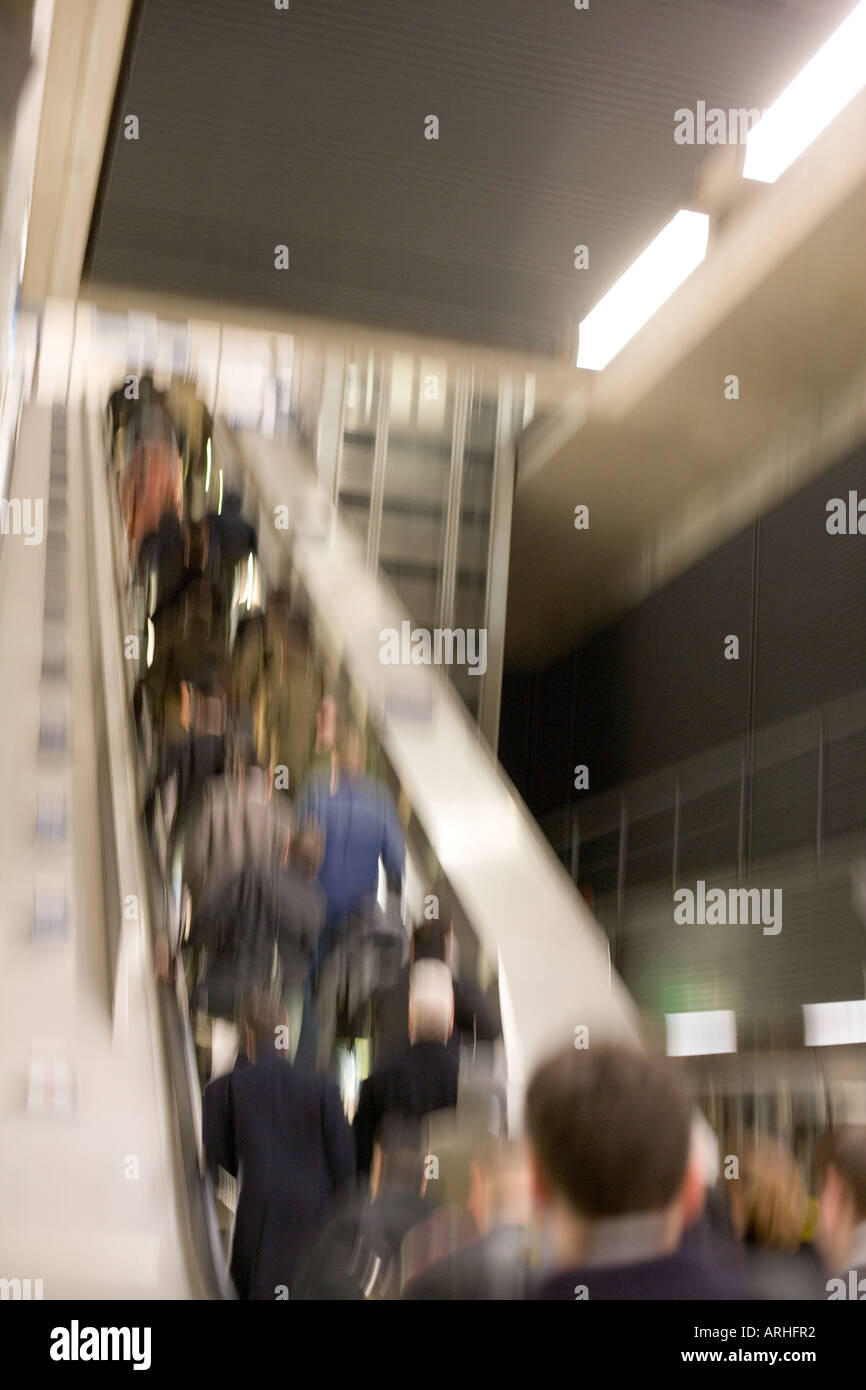 Motion-blurred crowd of commuters ascending a busy metro station escalator during rush hour ...