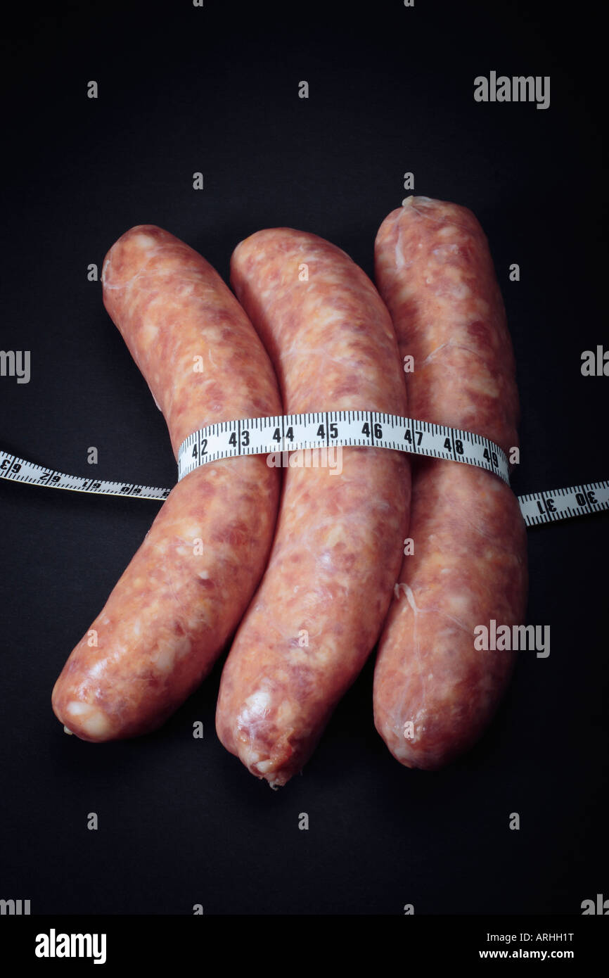 Three sausages with tape measure on black background Stock Photo - Alamy