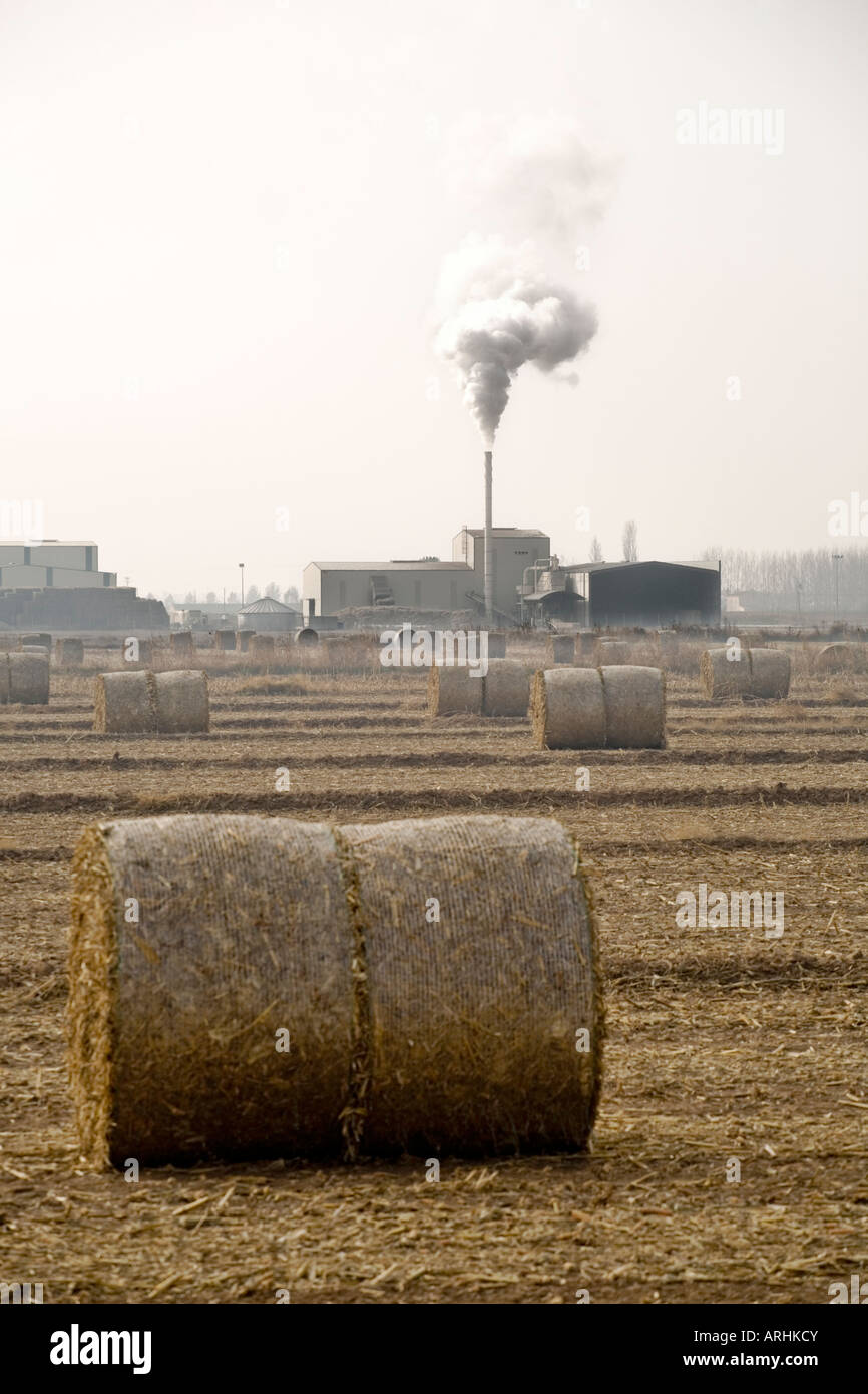 Hay roll and factory behind Stock Photo - Alamy