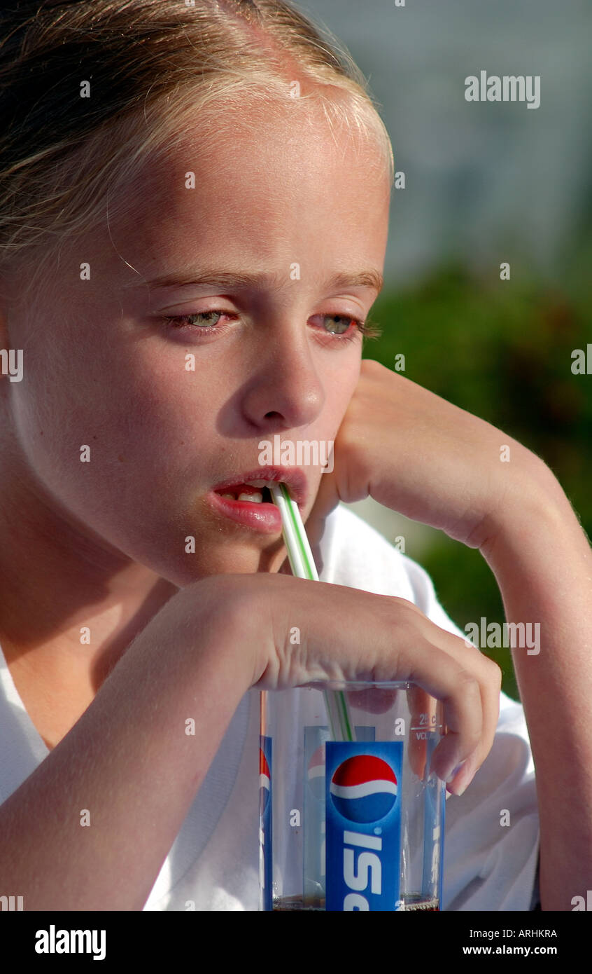 Sad Young Girl Drinking A Soft Drink Through A Straw Looking Down Stock