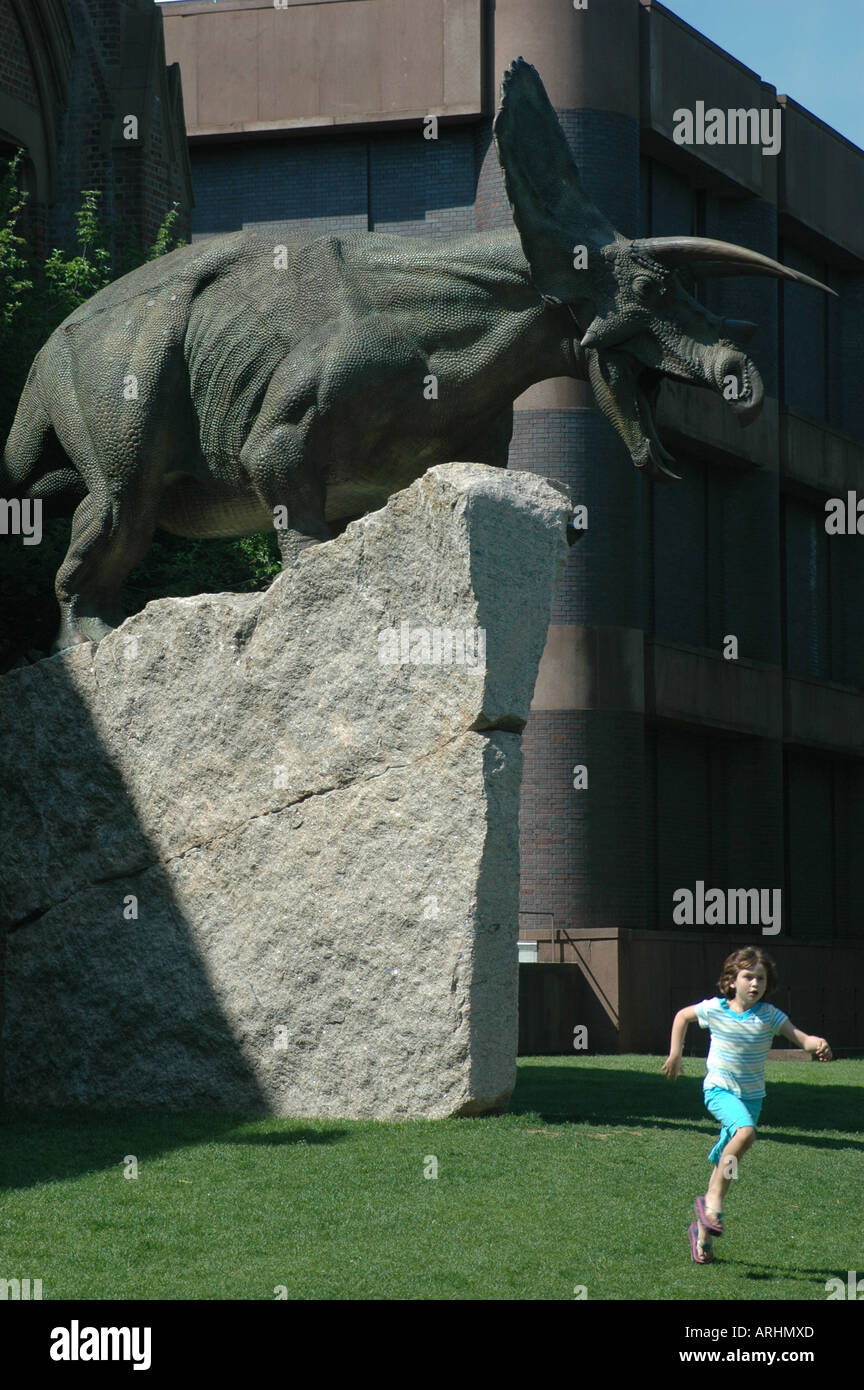 Little girl running in front of the statue of Torosaurus Latus in front ...
