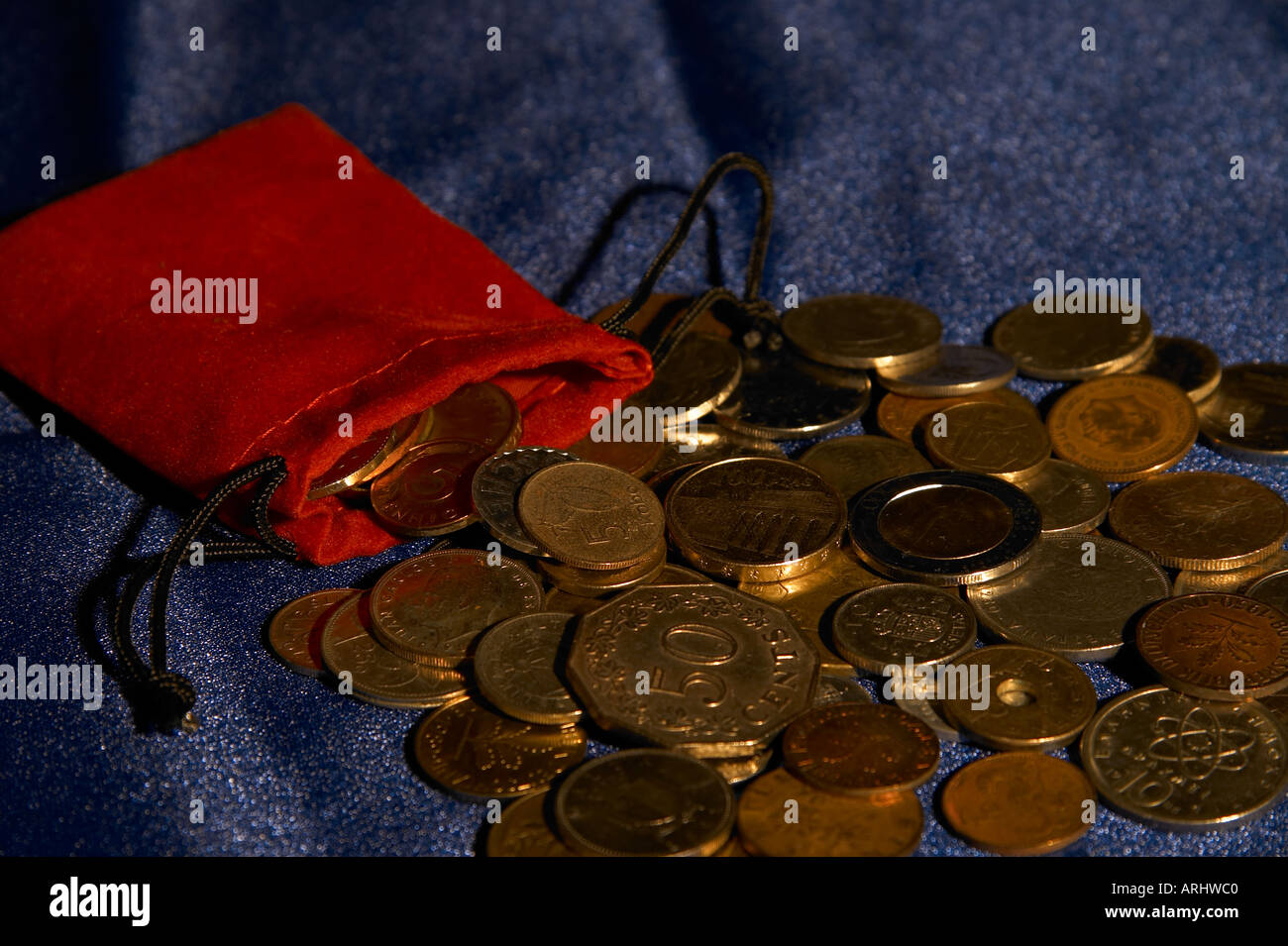 Coins spilling from a red bag Stock Photo - Alamy