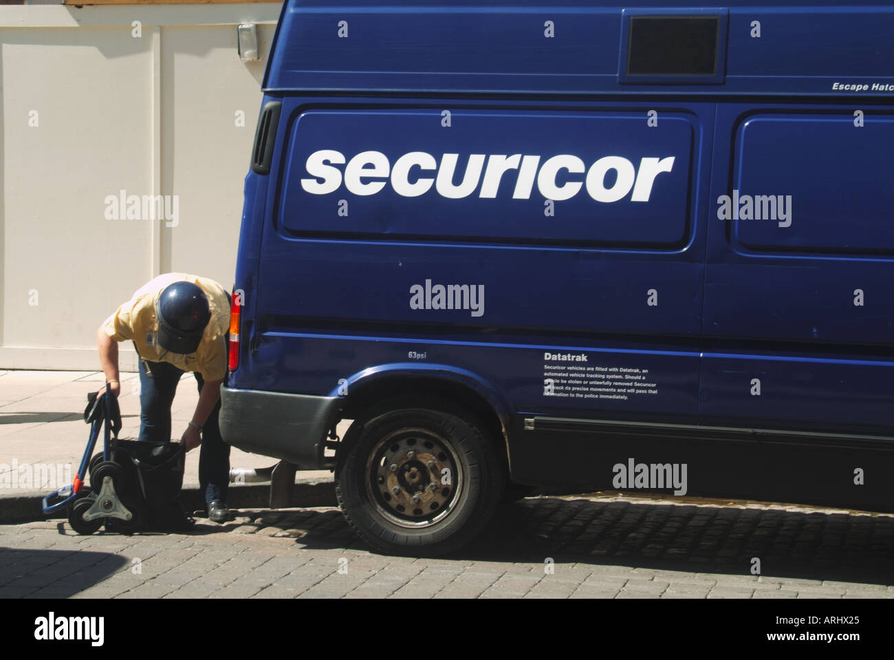 Close up of security personnel loading cash bags into rear of Securicor ...