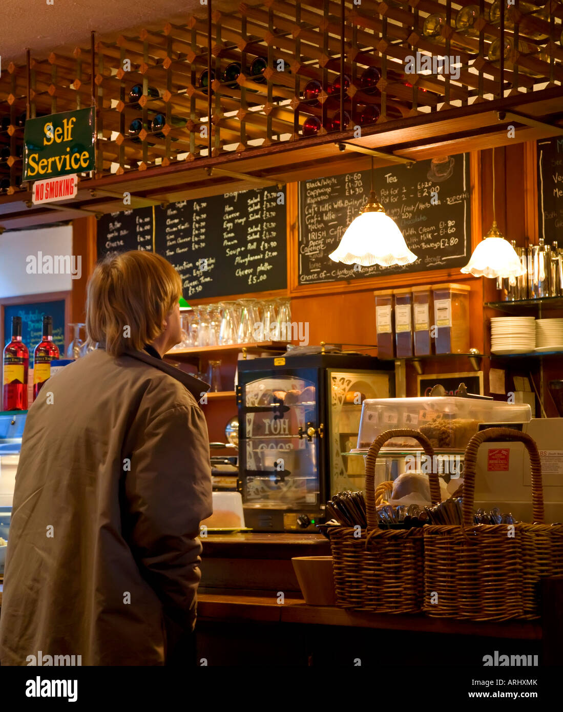 Person at counter choosing food on chalkboard menu in bistro Hay on Wye ...