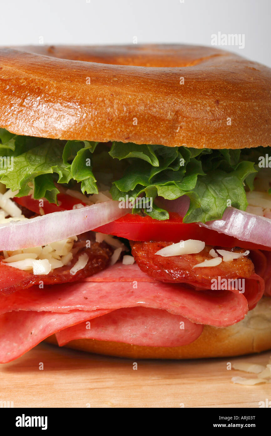 Cross section of bagel sandwich with ham fried bacon cheese lettuce ...