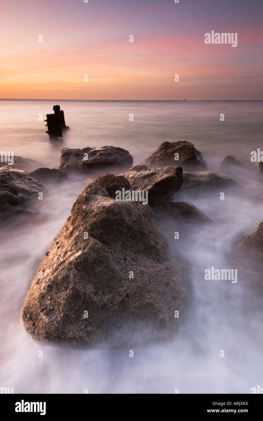 Water lapping over rocks in pre-dawn light on Hayling Island, Hampshire ...