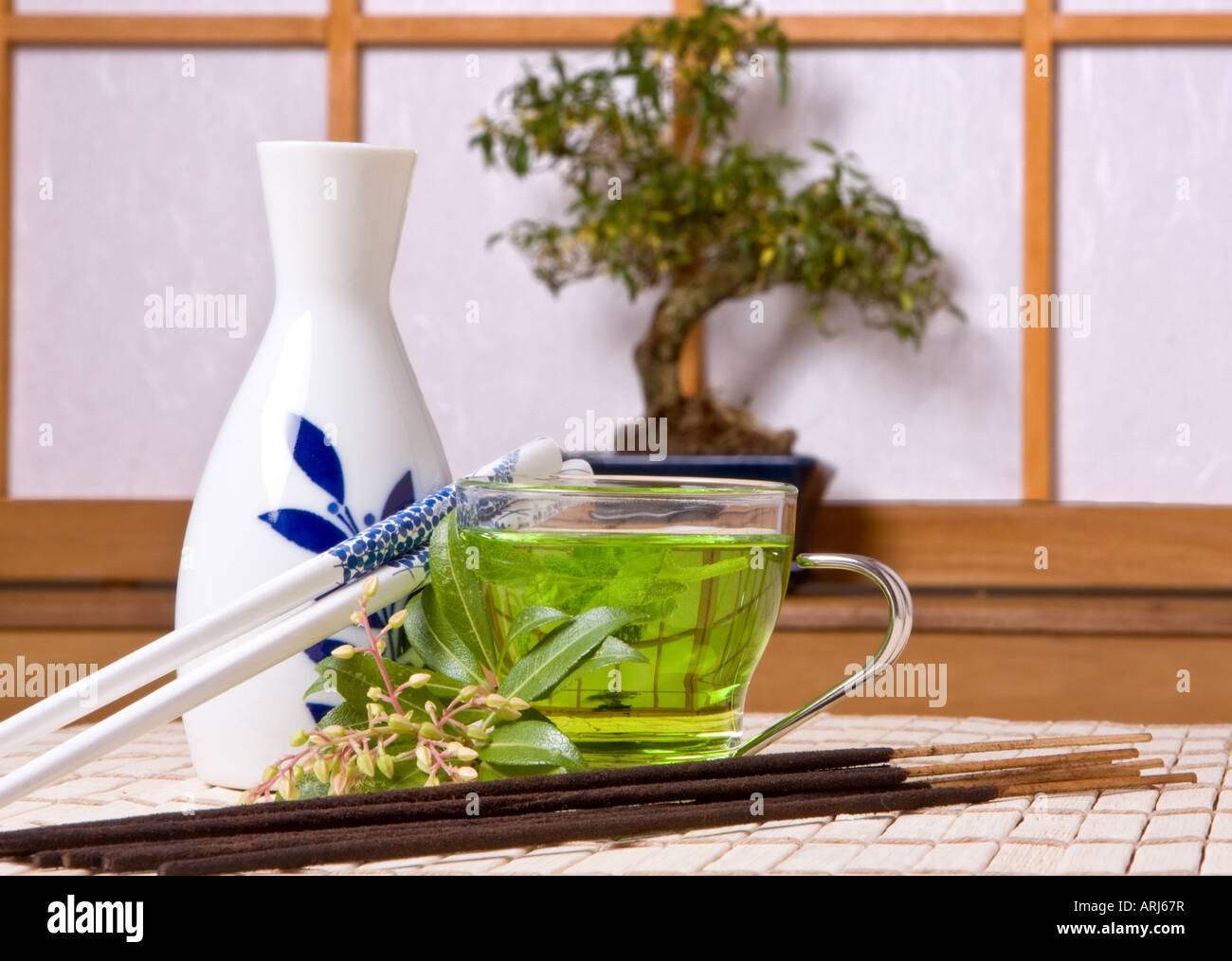 Sake, green tea, incense and bonsai tree against a traditional japanese ...