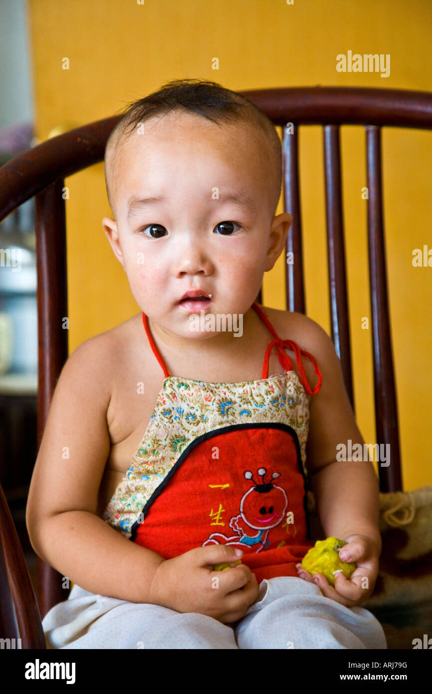 Mid shot young asian oriental peasant Chinese boy sitting looking to ...
