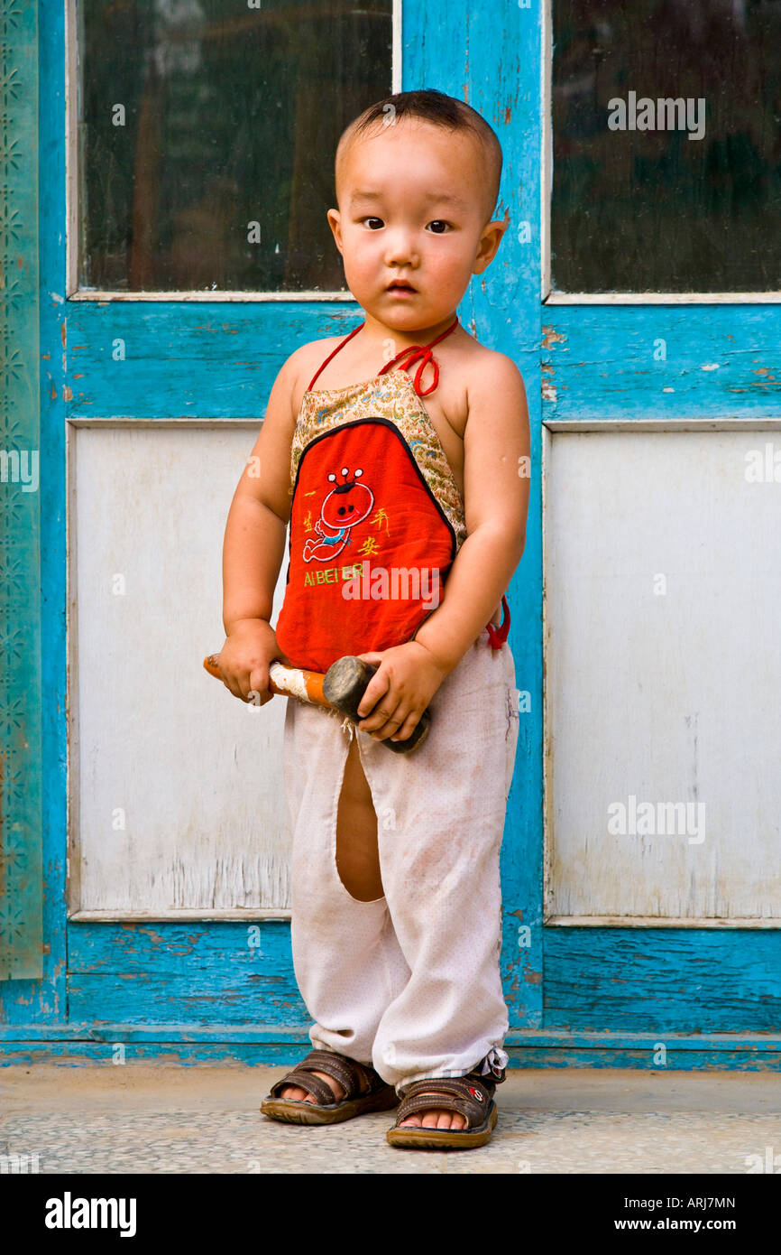 Young asian oriental peasant Chinese boy standing with hammer in hand ...
