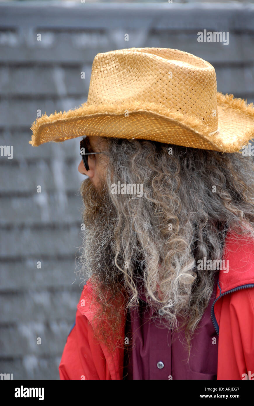 Homeless male with very long hair and a beard wearing a hat in downtown ...