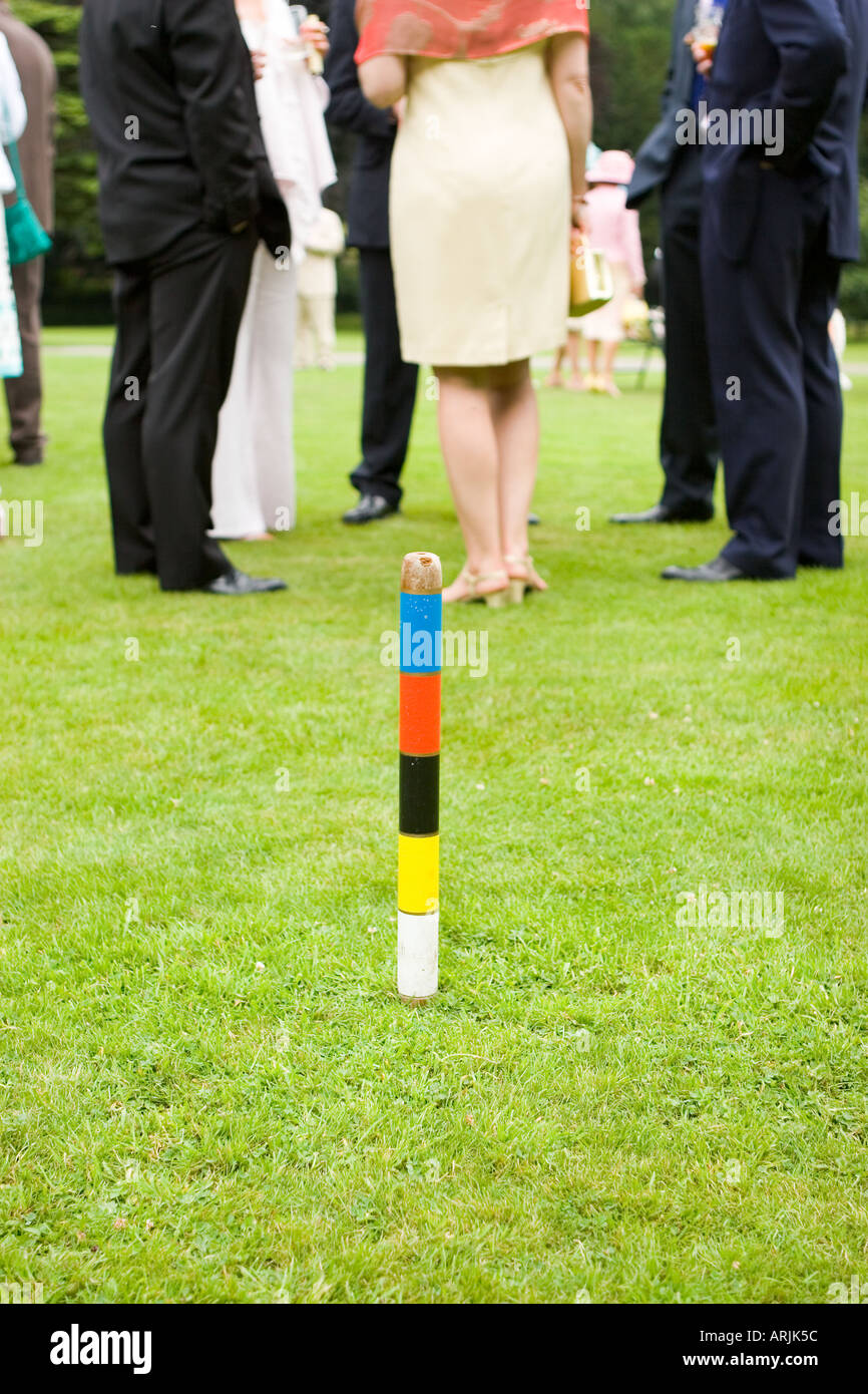 A painted croquet goal stake with wedding guests drinking Pimms in the ...