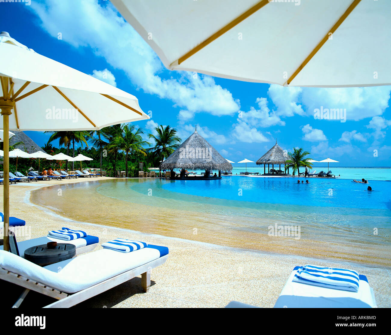 Resort pool with wigwams and beach parasols with chaises Stock Photo ...