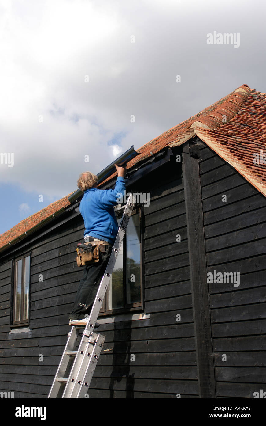New black cast iron guttering and downpipe being installed by a ...