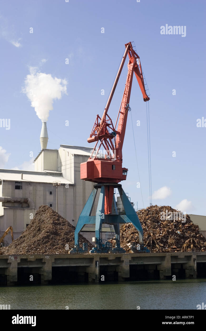 Crane on quayside unloading scrap metal into trucks for reprocessing ...