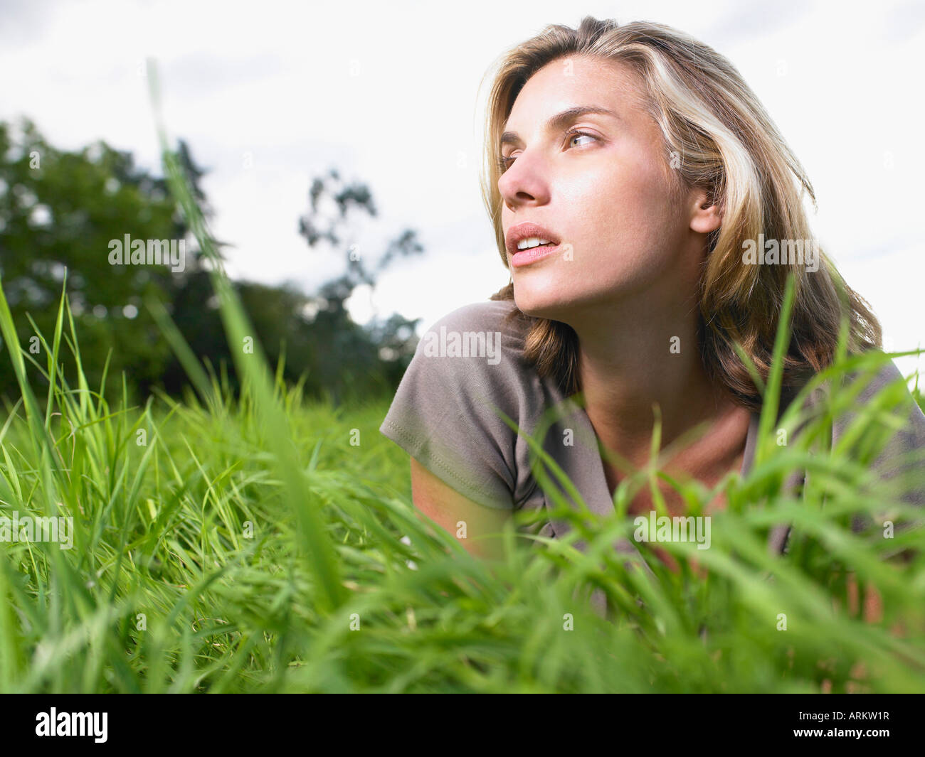 Woman laying in a green field portrait Stock Photo - Alamy