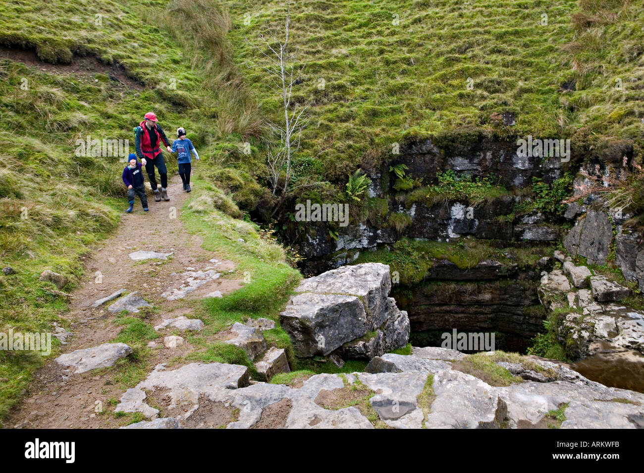 Man and two children near the entrance shaft to Gaping Gill cave ...