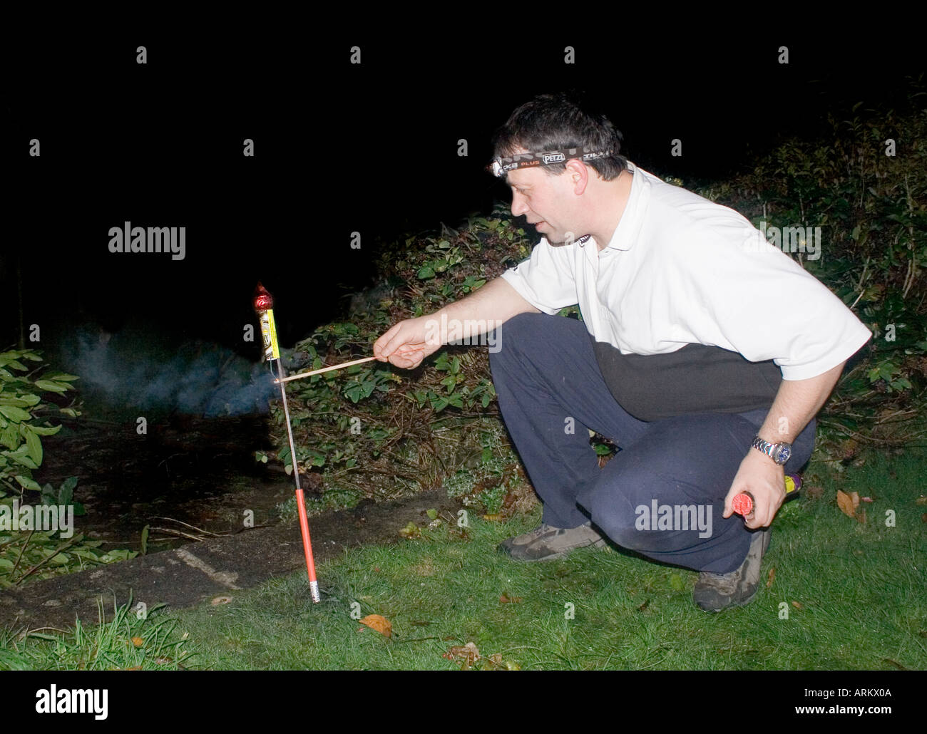 Adult man lighting a firework rocket in a garden display UK Stock Photo ...