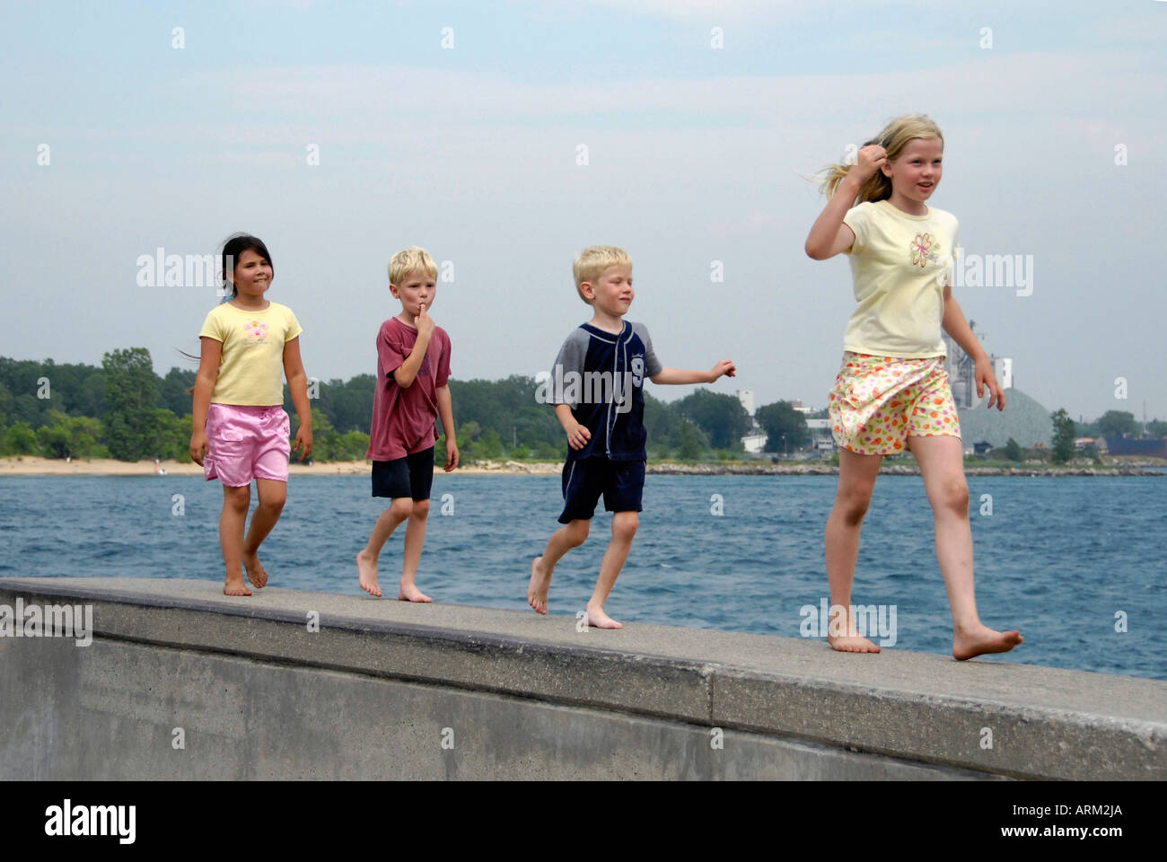 4 kids walk and balance on a cement beam Stock Photo - Alamy