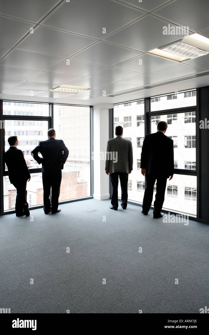 Business men looking out of the windows at the view in a new office ...