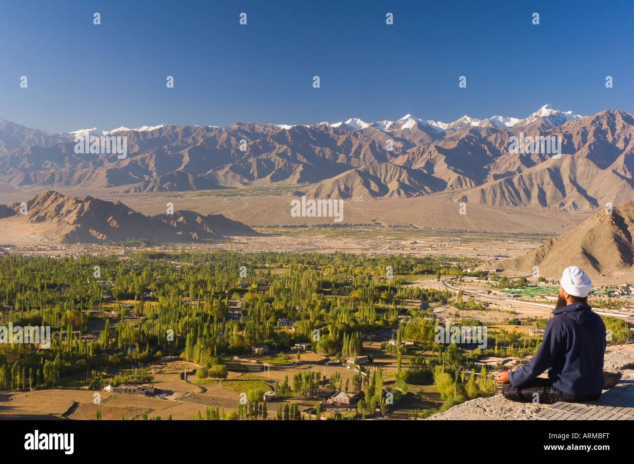 Man meditating, with view of Indus Valley and Stok-Kangri massif, Leh ...