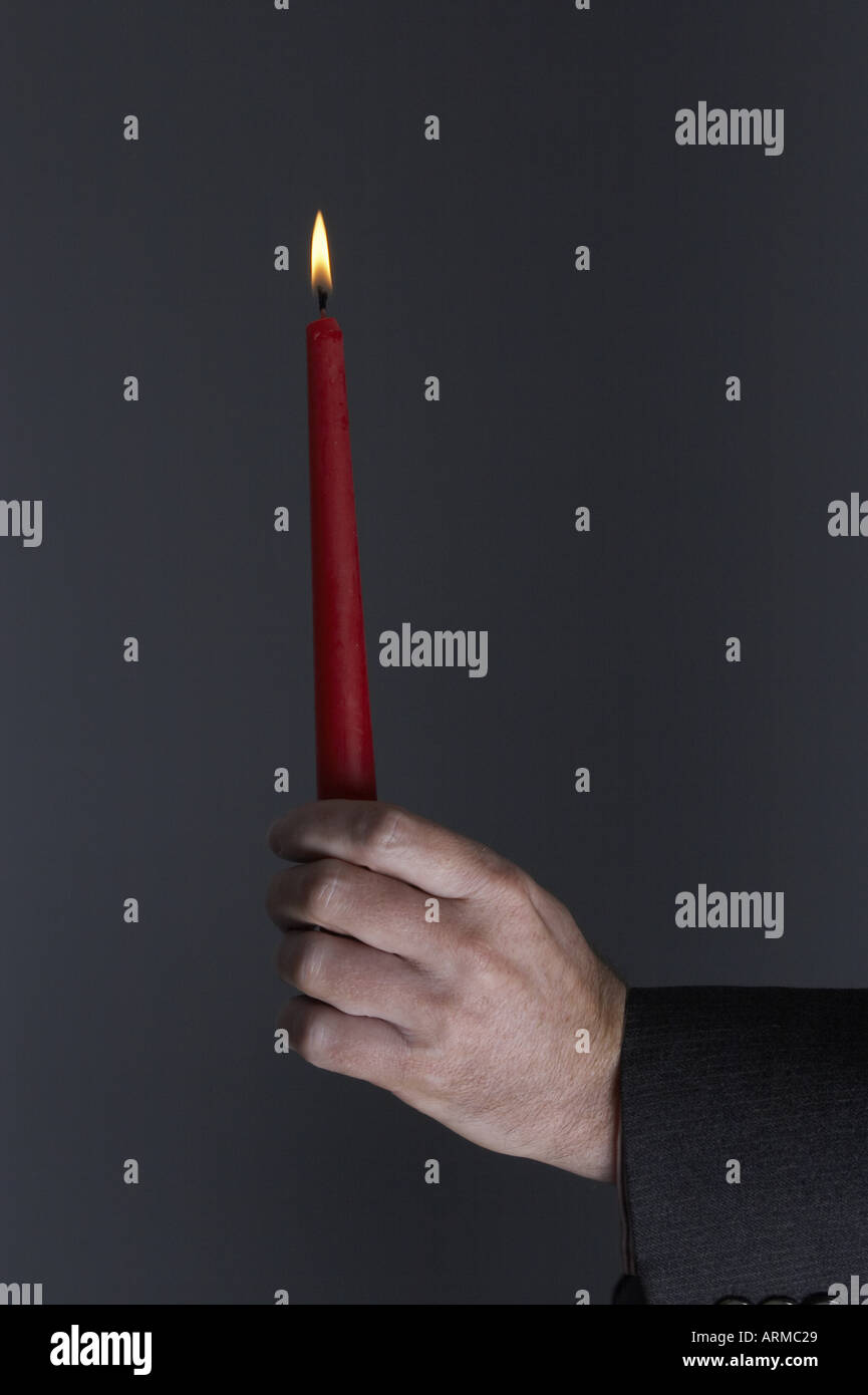 Male man in a suit holding a red lit candle in his hand Stock Photo - Alamy