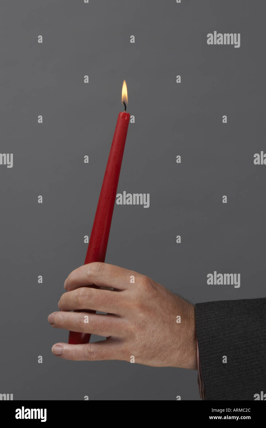 Male man in a suit holding a red lit candle in his hand Stock Photo - Alamy