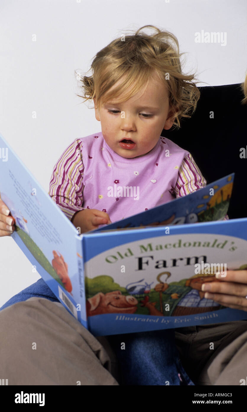 girl sat on mums knee reading storybook uk Stock Photo - Alamy