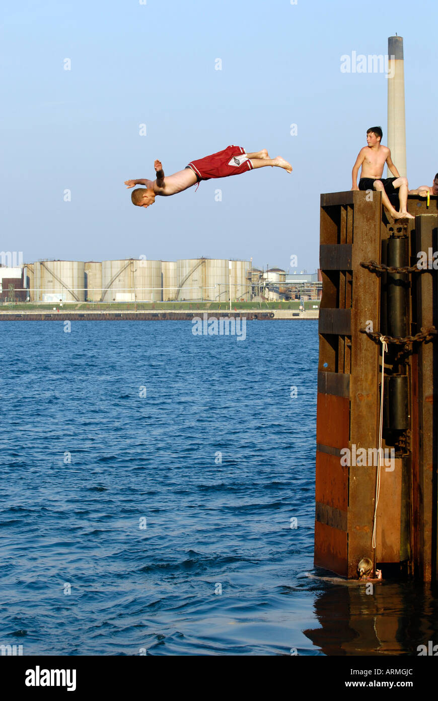 teenage boy jumps and dives off of a high piling into a river Stock ...