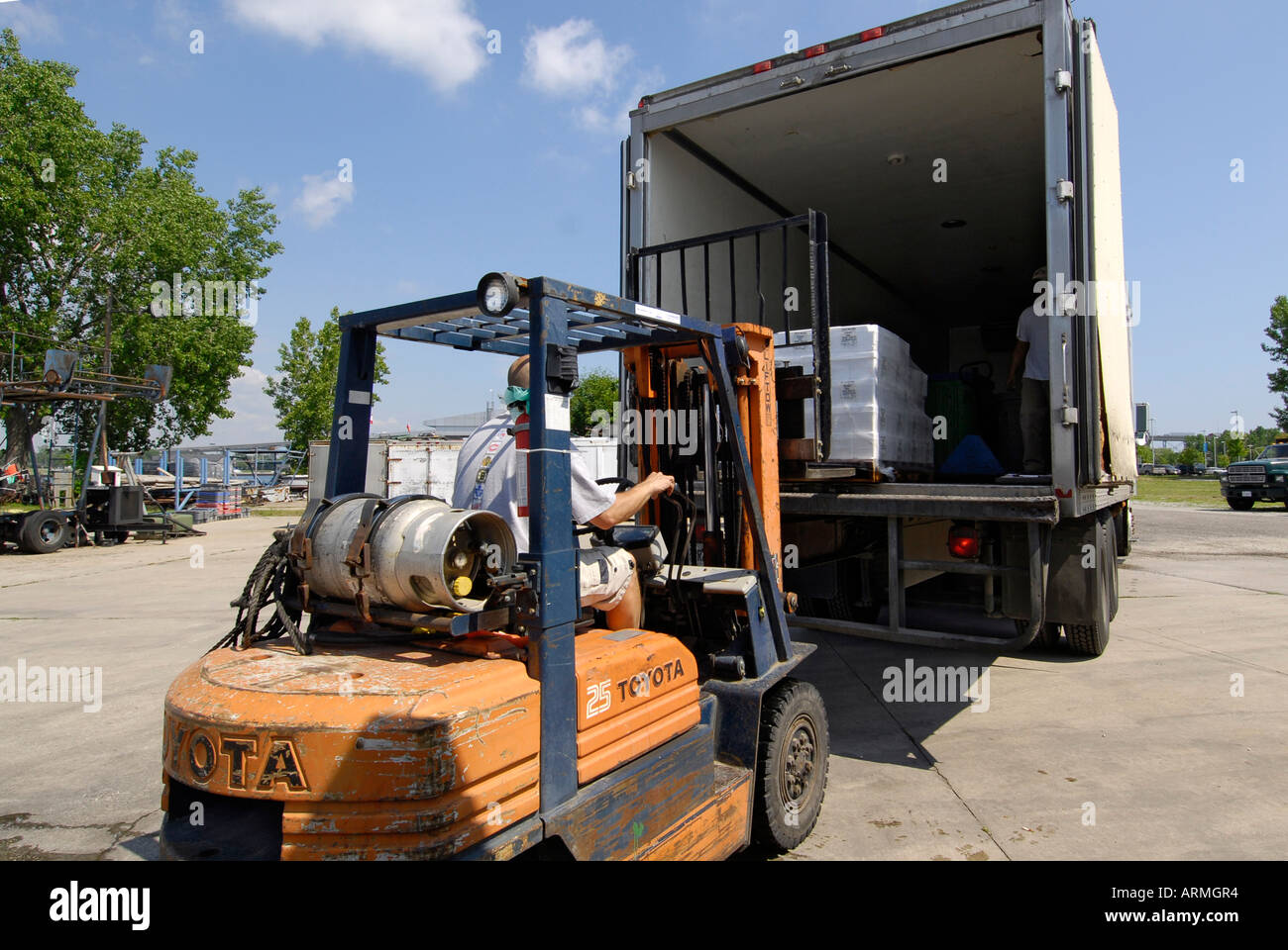 Forklift operator unloads a pallet of goods from a semi tractor trailer ...