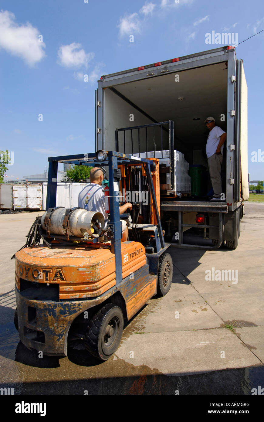 Forklift operator unloads a pallet of goods from a semi tractor trailer ...