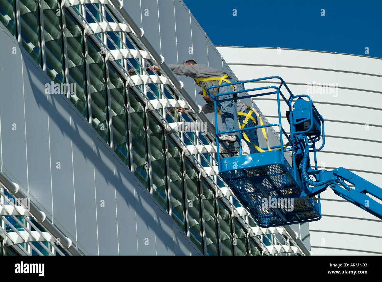 Window washers use mechanical industrial boom to elevate them against ...