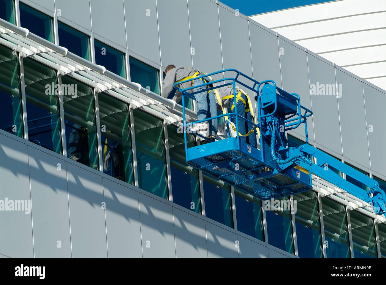 Window washers use mechanical industrial boom to elevate them against ...