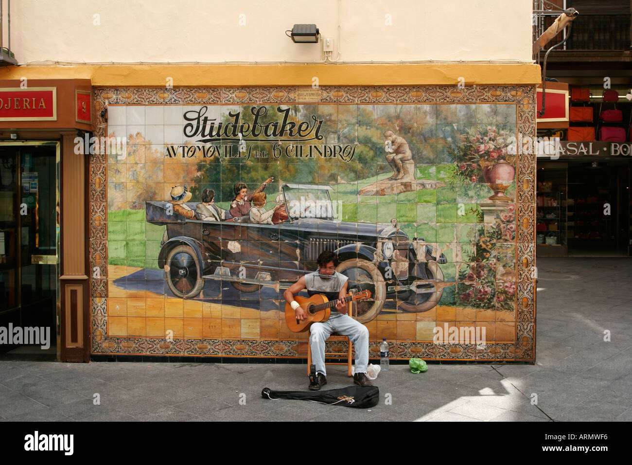Busker musician by Azulejo tiles advertising Studebaker cars on a wall ...